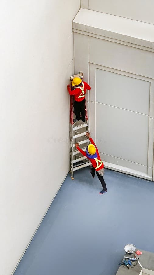 Local Construction Workers Working As Buddy, One Climbing a Step Ladder ...