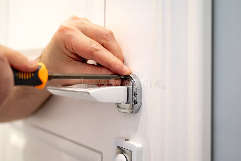 A Locksmith Adjusts the Door Handle of a Modern White Interior Door ...
