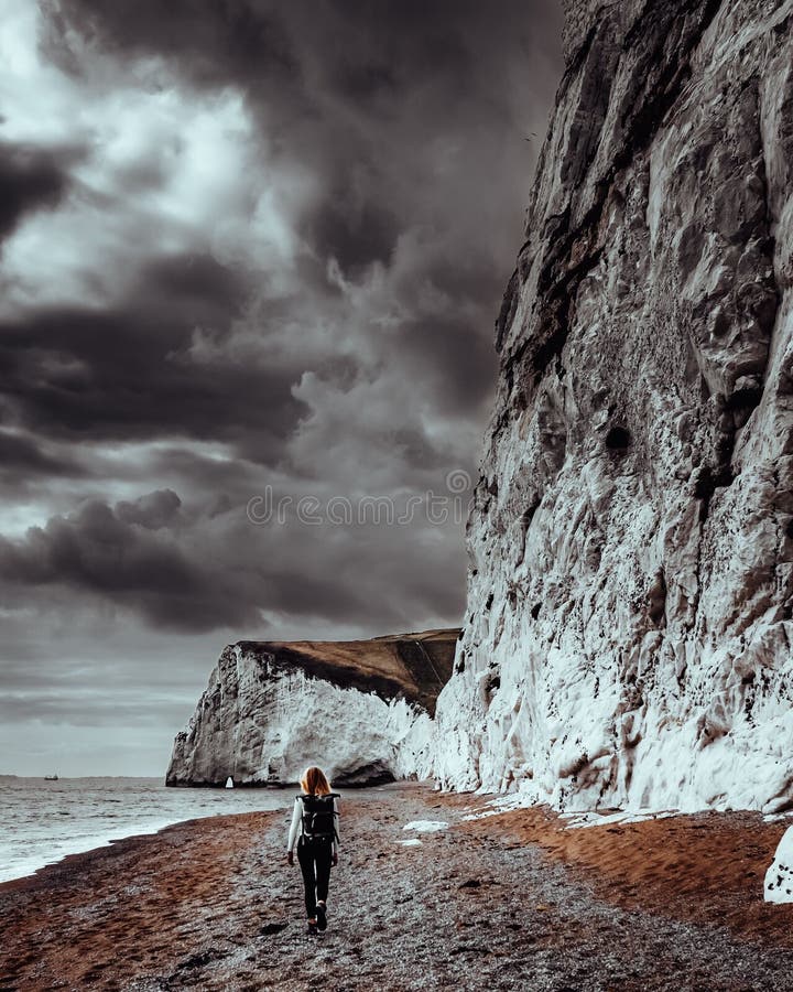 Lone Female Hiker Walks Along the Dramatic White Cliffs Under a Stormy ...