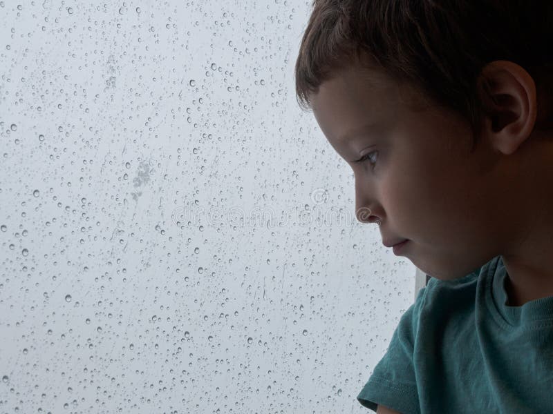 A Lonely Child Sits by the Window, Looking Out Thoughtfully. Soft Light ...