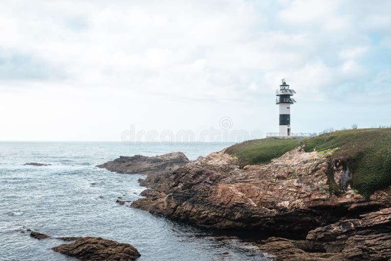 Lonely Lighthouse on Rocky Cliff Facing the Ocean during a Cloudy Day ... Lonely Lighthouse on Rocky Cliff Facing the Ocean during a Cloudy Day ...