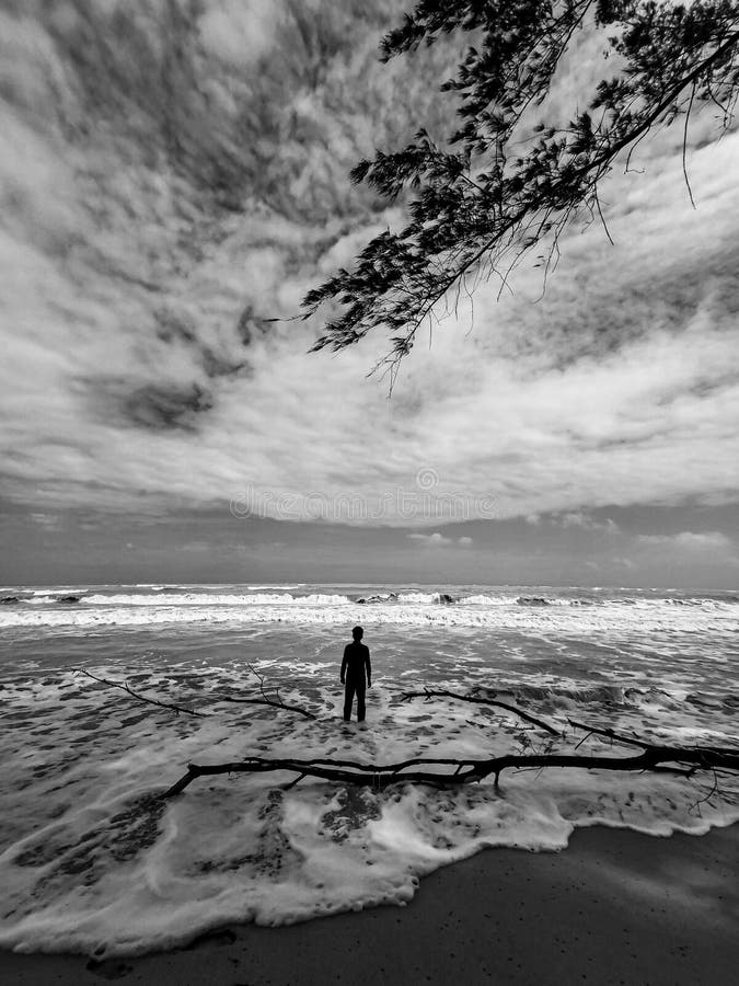 A Lonely Man Standing in the Waves while Watching the Sky Stock Image ...