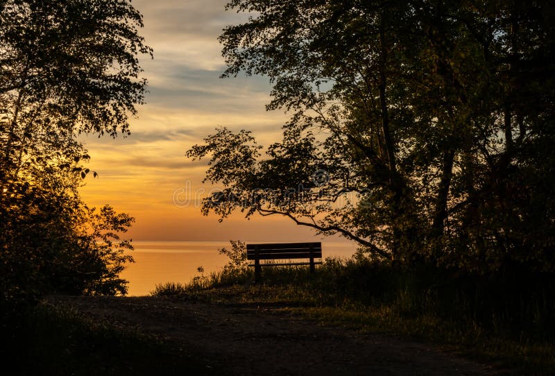 Lonely Park Bench Overlooking Setting Sun and Calm Lake Stock Image ...