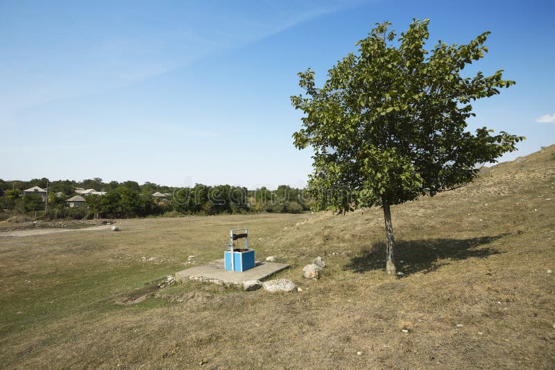 Lonely well and tree stock image. Image of brown, blue - 176582541