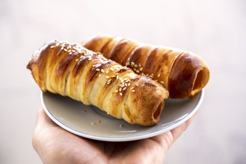 Long Bun with Sesame Seeds on a Plate Hand Stock Photo - Image of diet ...