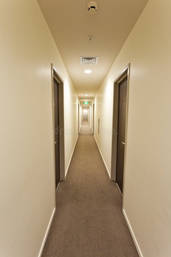 Long Corridor with Hotel Room Doors and Exit Sign Stock Image - Image ...