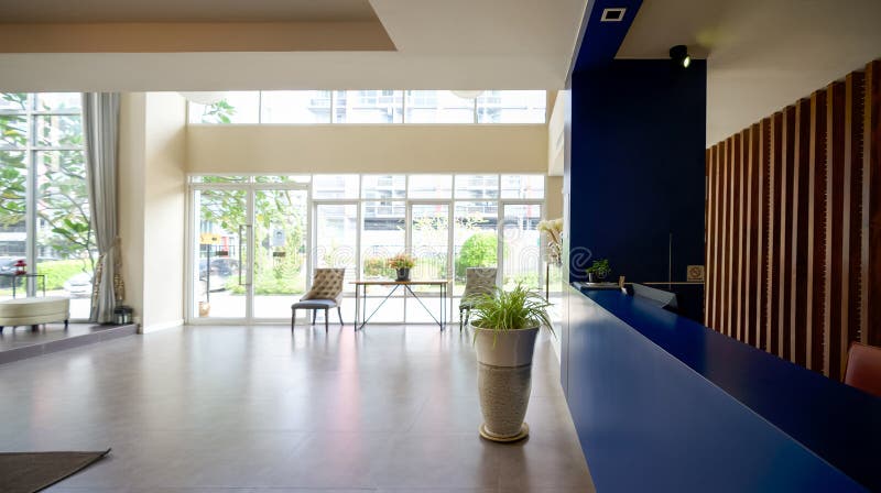 A Long Dark Blue Reception Counter is Located beside the Hotel Lobby ...