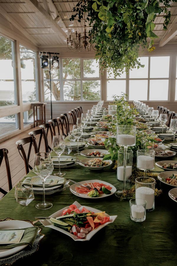 A Long Dining Table Set with Beautiful Plates, Glasses, and Candles ...