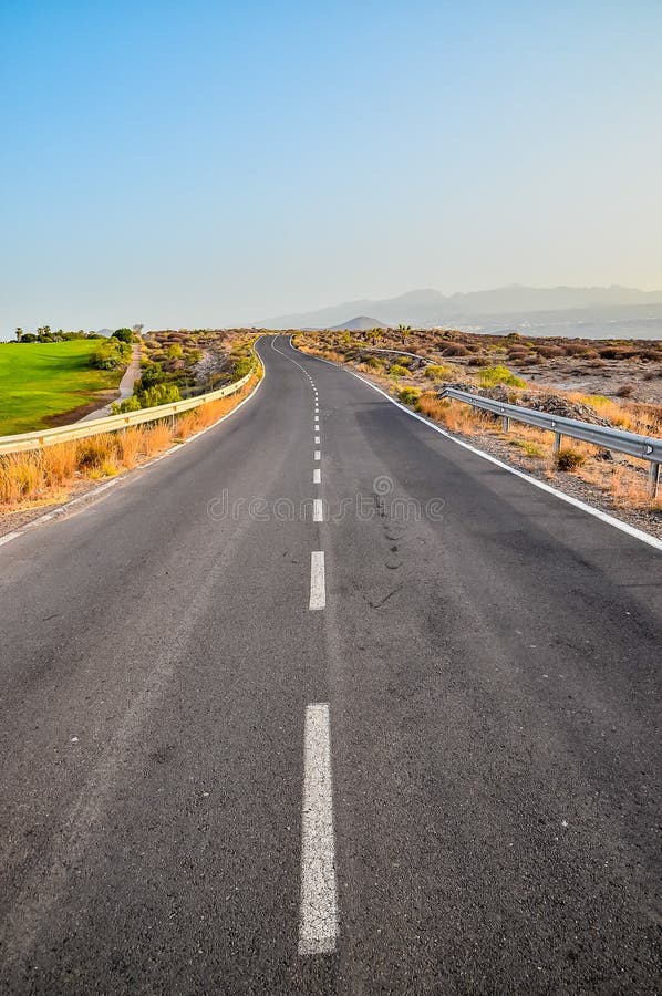 A Long, Empty Road with a Blue Sky in the Background Stock Photo ...