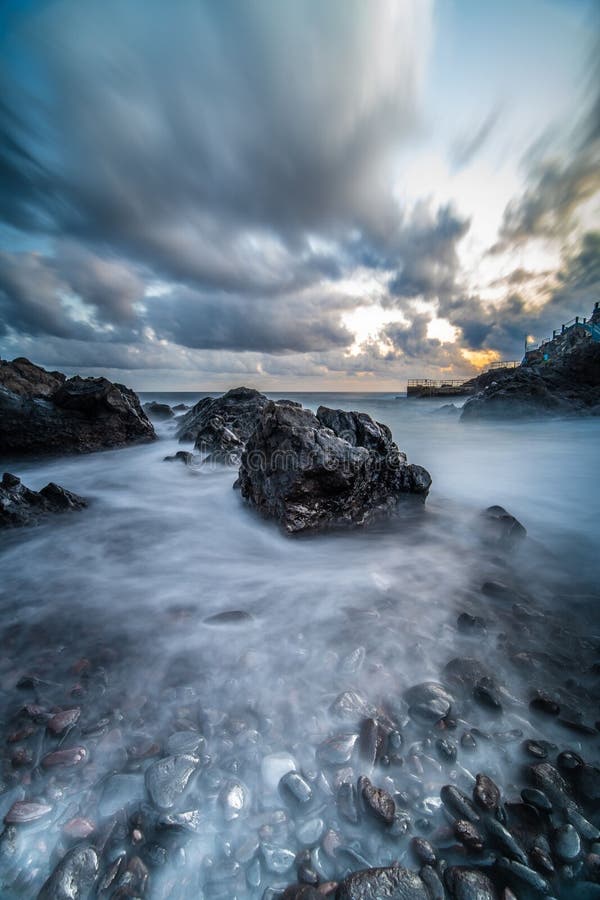 Long Exposure of Clouds and Waves on a Rocky Beach during the Sunset ...