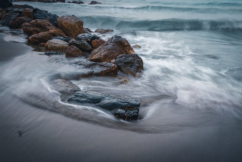 Long Exposure Effect of Ocean Waves Hitting the Sandy Beach with Stones ...