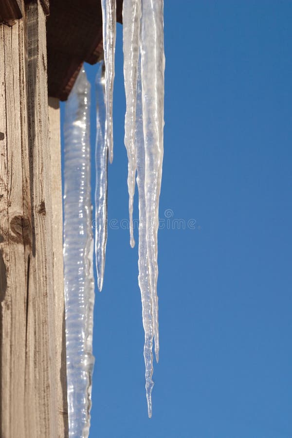Long Icicles Hangs from a Roof Over Blue Cloudless Stock Image - Image ...