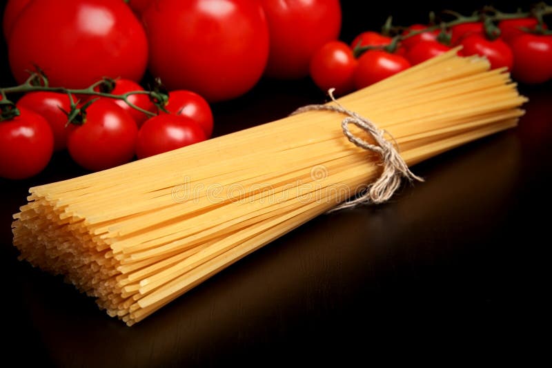 Long Pasta Raw Isolated on Black Table with Tomatoes Stock Image ...