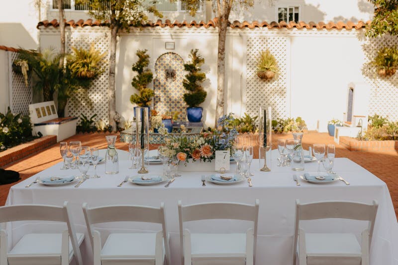 A Long, Rectangular Table Covered in a White Tablecloth is Set for a ...