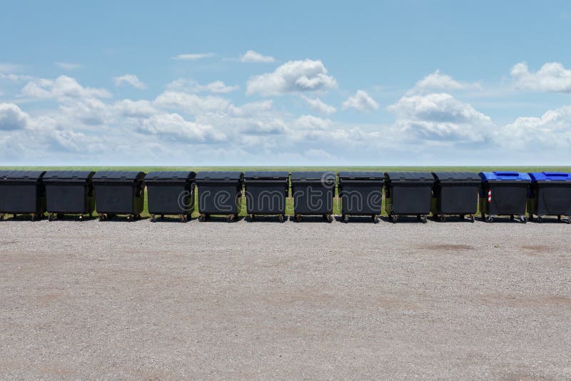 Long Row of Black Garbage Containers Outside Under the Blue Sky with ...
