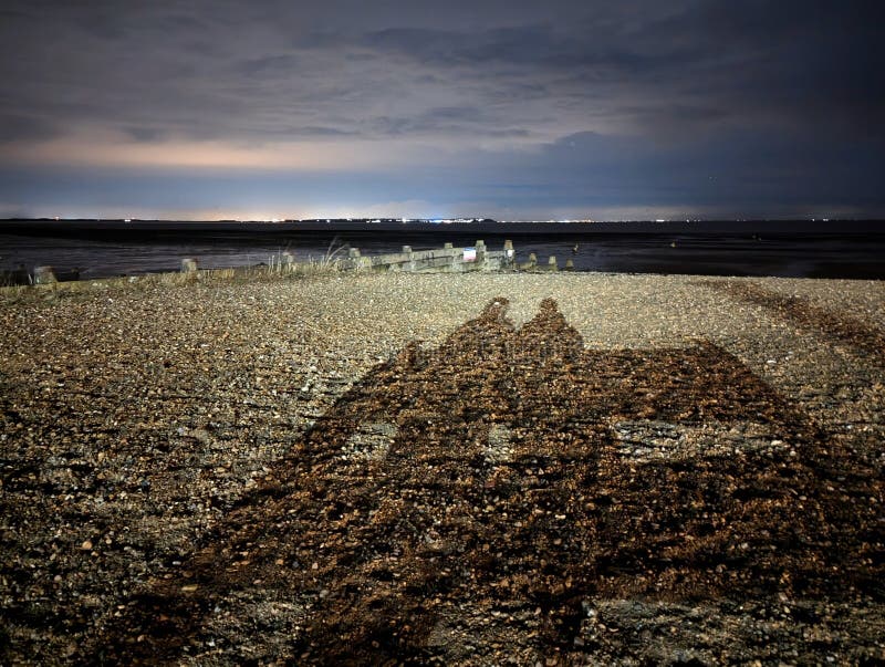 Long Shadows on the Beach of 2 People Sitting on a Seat. Stock Photo ...