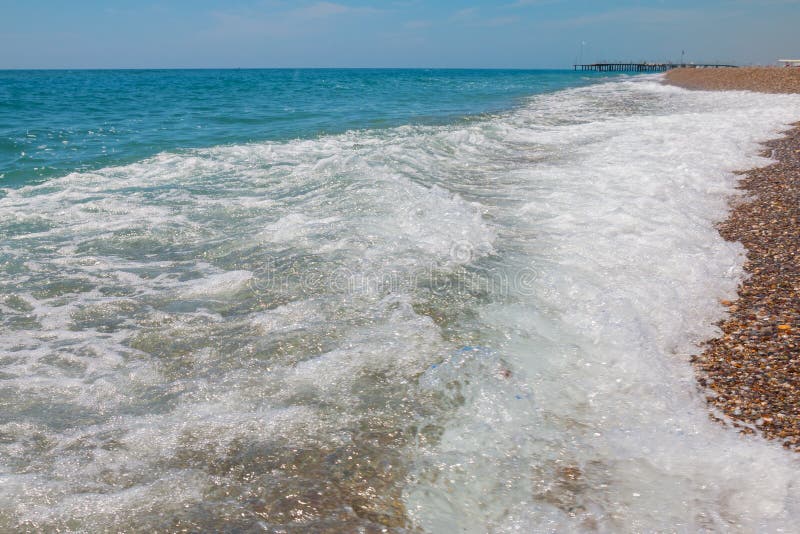 Long Waves Along Rocky Beach with Pier in the Distance Stock Image ...