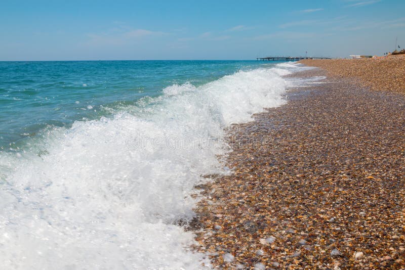 Long Waves Along Rocky Beach with Pier in the Distance Stock Photo ...