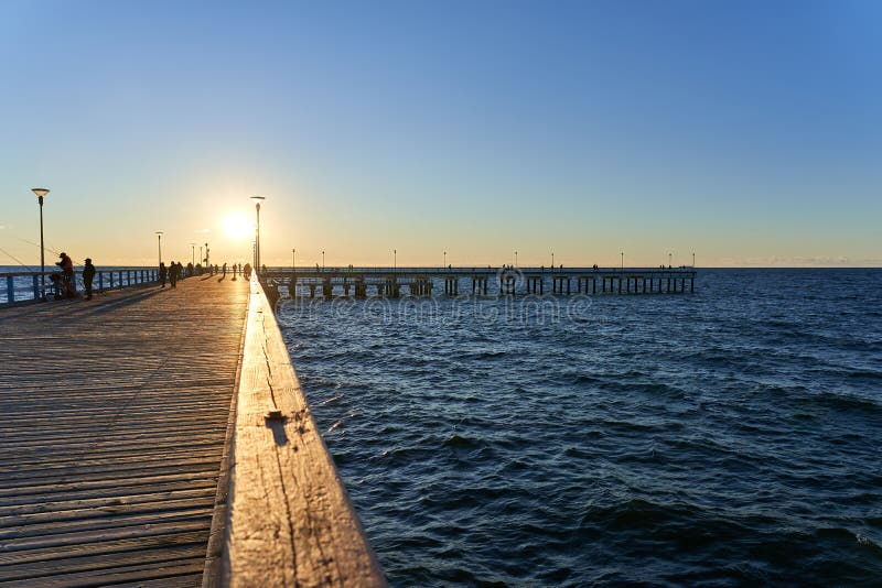 A Long Wooden Pier at Sunset with Silhouettes of People Stock Photo ...