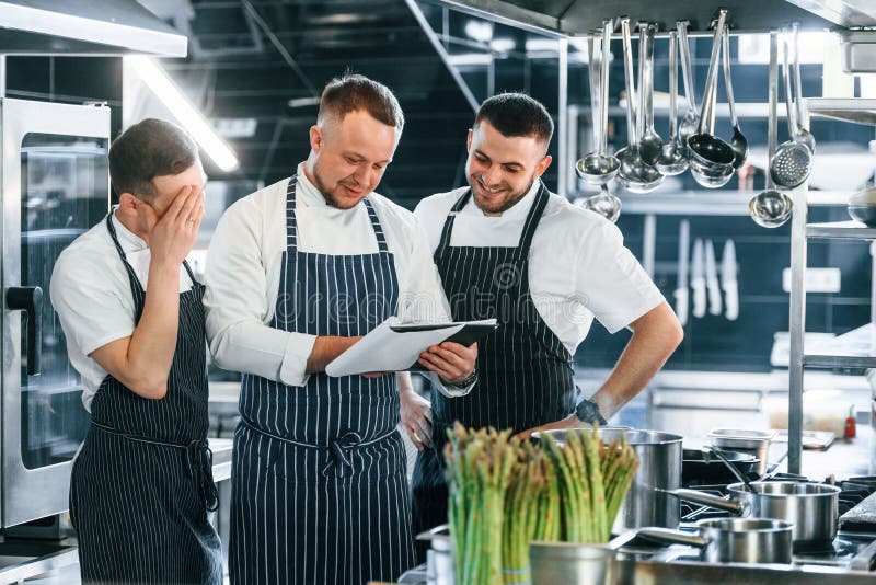 Looking at the Documents. Kitchen Workers is Together Preparing the ...
