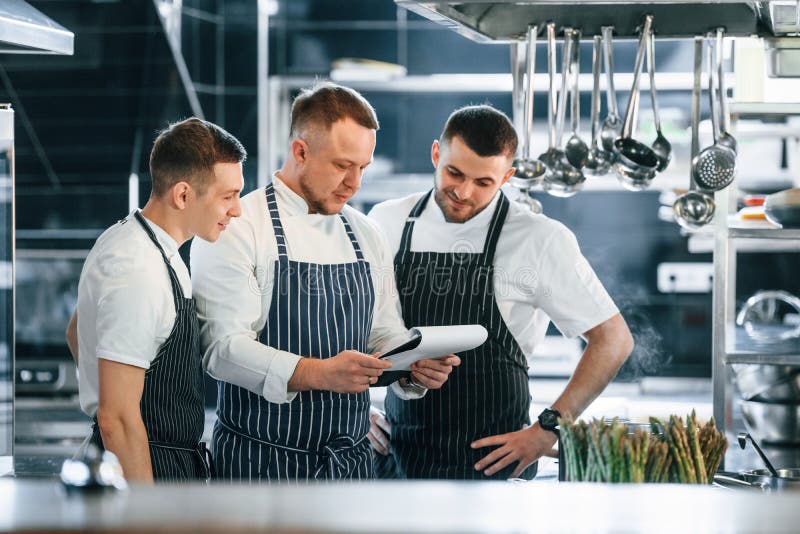 Looking at the Documents. Kitchen Workers is Together Preparing the ...