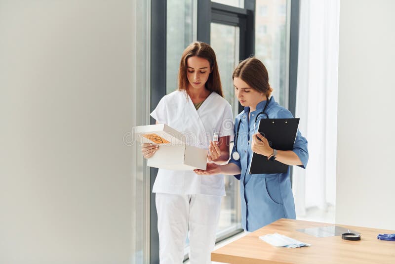 Looking at Documents. Two Doctors in Uniform Standing Indoors and ...
