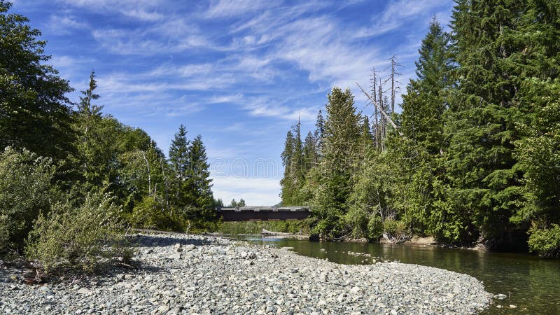 Looking Down a River To a Remote Logging Road Bridge with Wispy Clouds ...