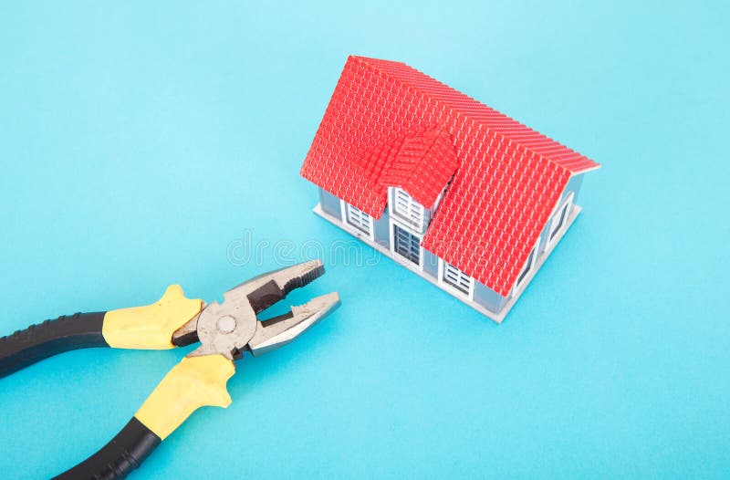 Looking Down on a Small House Model and a Pair of Pliers Tool on a Blue ...