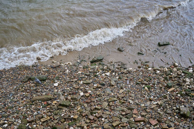 Looking Down at Small Waves Breaking on Rocks and Stones on River Bank ...