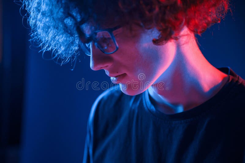 Looking Down. Young Man with Curly Hair is Indoors Illuminated by Neon ...