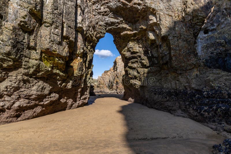 Looking through a Natural Rock Arch at Perranporth Beach in Cornwall ...