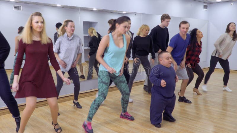 Young Group of People and Little Man Dances Together in Light Studio ...