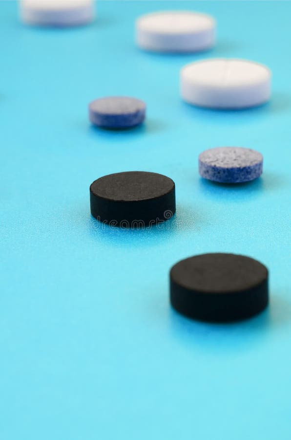 A Lot of White, Black and Grey Tablets Lie on the Blue Surface ...