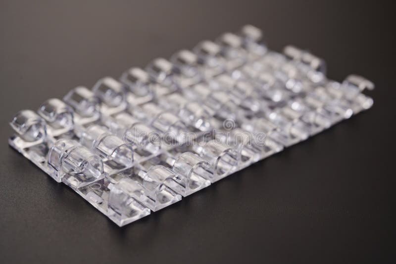 Lots of Clear Plastic Wire Holders on the Black Surface. Stock Photo ...