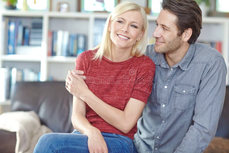 Love Hug And Couple On Sofa In Living Room Together For Happiness