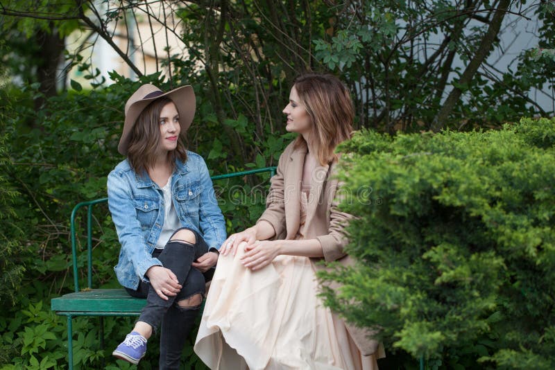 Lovely Friends Talking and Sitting on a Park Bench Outdoors Stock Photo ...