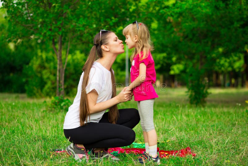 Lovely Little Daughter Kiss Mother. Outdoor Portrait of Happy Family ... Lovely Little Daughter Kiss Mother. Outdoor Portrait of Happy Family ...