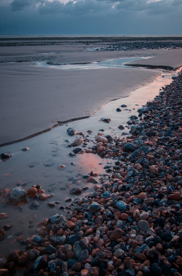 Sunset on pebble beach stock image. Image of stone, water - 112108649