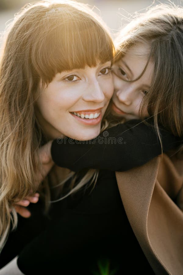 Loving Mother And Daughter Gently Hug Each Other On The Beach At Sunset