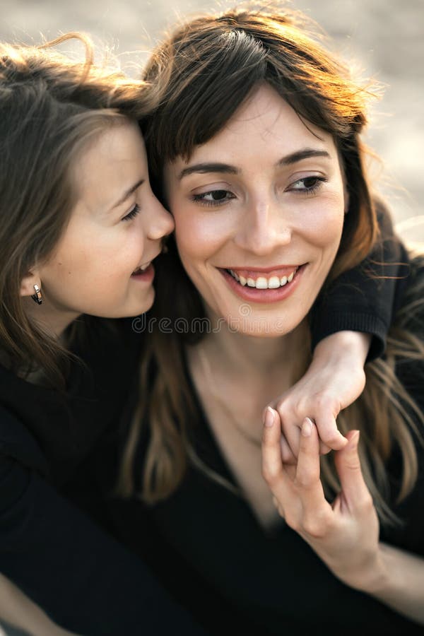 Loving Mother And Daughter Gently Hug Each Other On The Beach At Sunset
