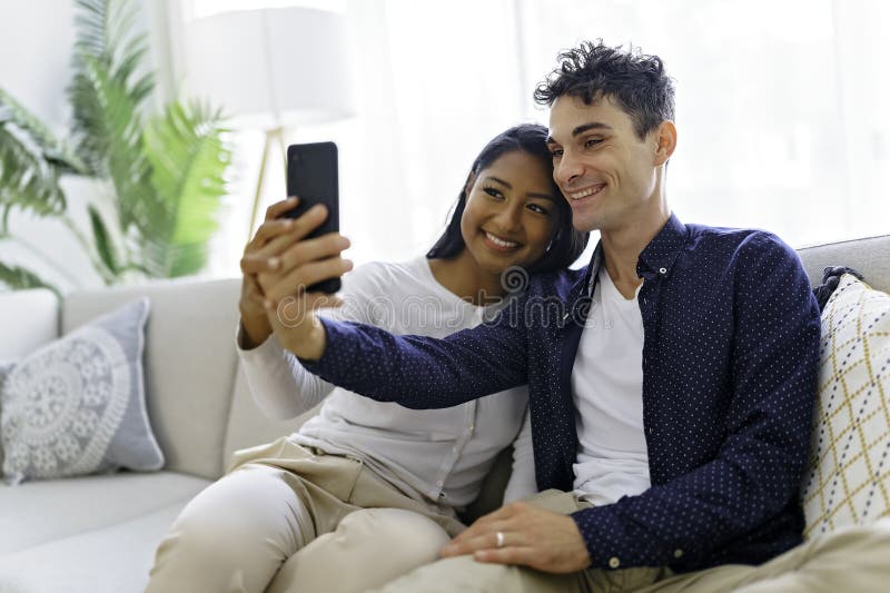 Loving Young Couple Sitting on the Couch at Home and Using Telephone ...