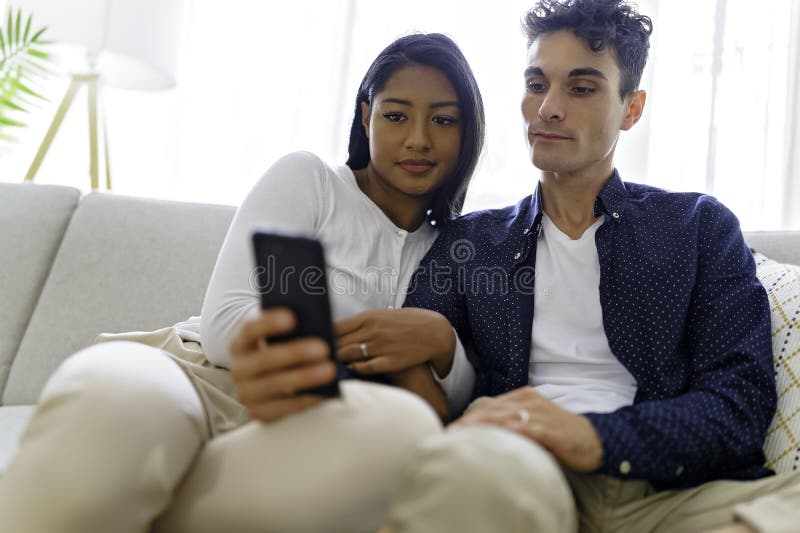 Loving Young Couple Sitting on the Couch at Home and Using Telephone ...