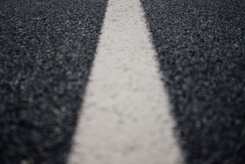 Low Angle Close-up of a White Paint Line on the Center of a Black ...