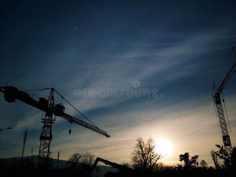 Low-angle of Crane Silhouettes at Sunrise with Clear Sky Background ...