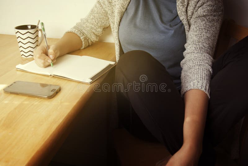 Low Angle of Joyful Woman Sitting at Kitchen Table and Making Notes in ...