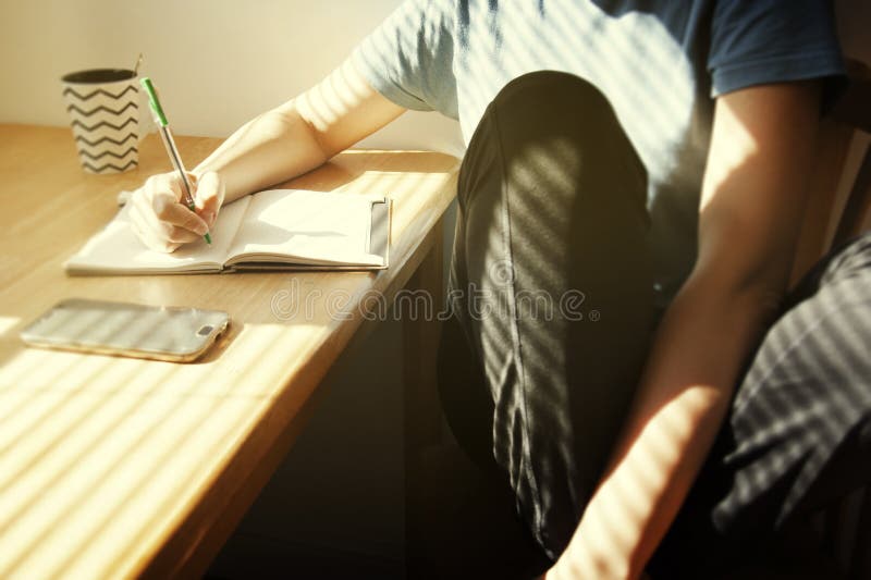 Low Angle of Joyful Woman Sitting at Kitchen Table and Making Notes in ...