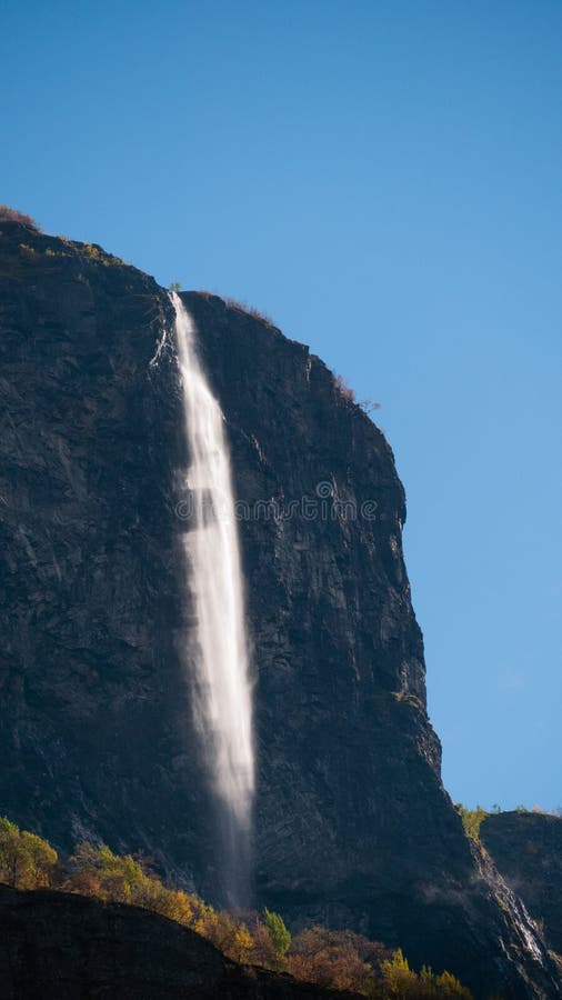 Low Angle Panoramic View of a High Cliff with a Waterfall Under a Clear ...