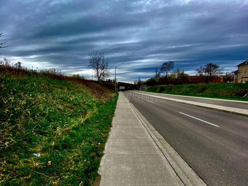 Low-angle of a Road with Green Grass Around, Cloudy Gloomy Sky ...