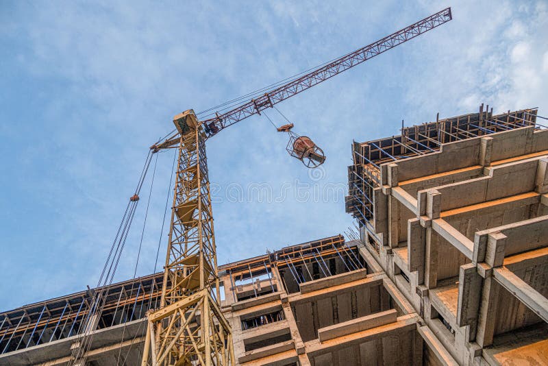 Low Angle Shot of a Crane with Equipment on a Construction Site with a New Building ...