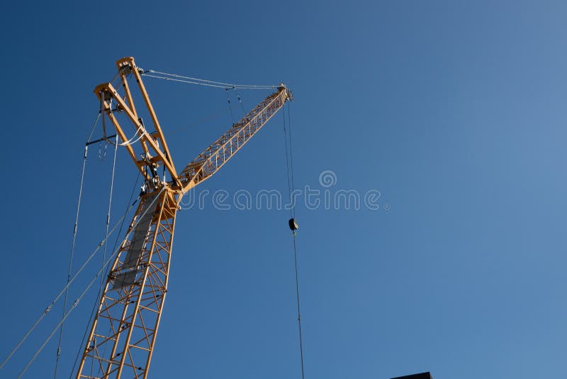 Low Angle Shot of a Crane Under a Blue Sky with Several Metal Cords ...